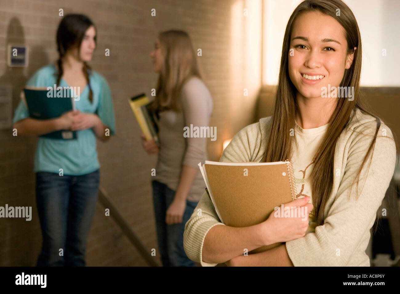 Three students standing in a corridor Stock Photo - Alamy