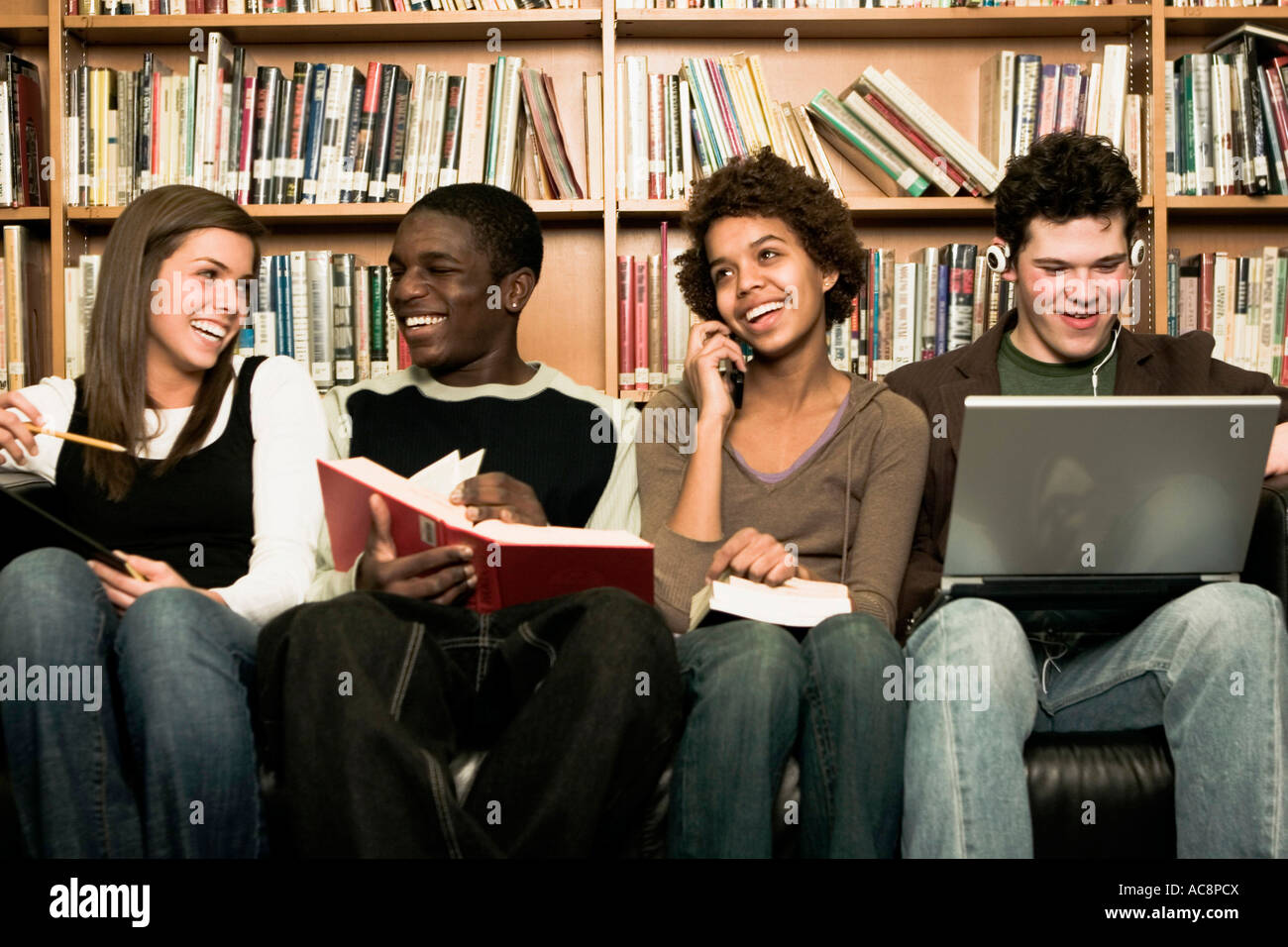 Four students sitting on a couch in a library Stock Photo - Alamy