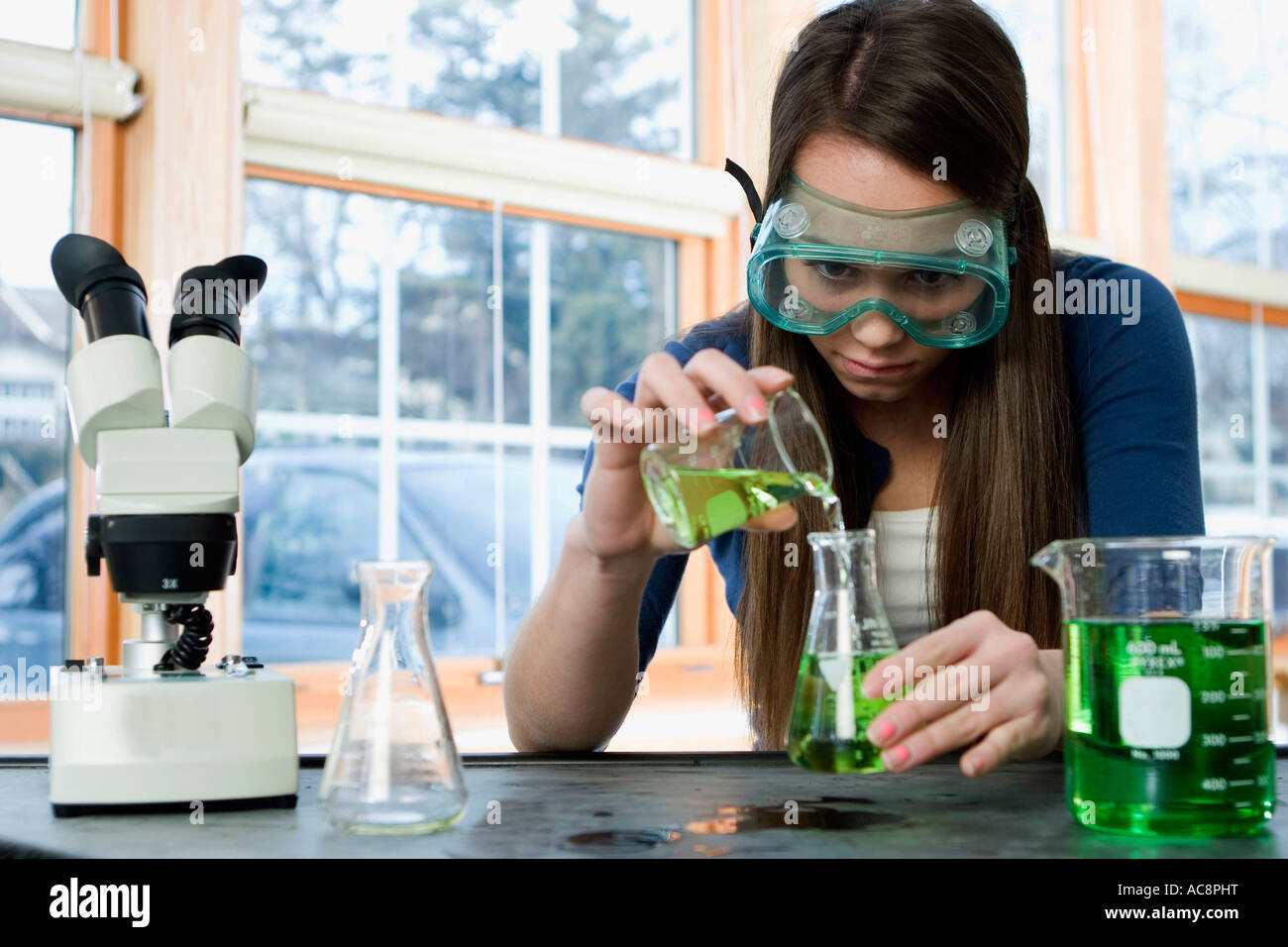 Student pouring liquid in to a beaker in a science lab Stock Photo - Alamy
