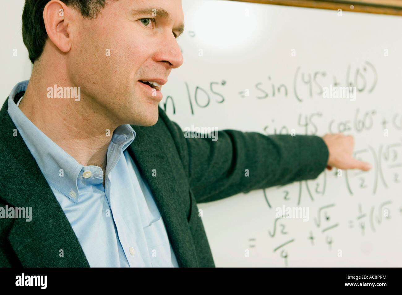 Male teacher pointing to a math equation on a whiteboard Stock Photo ...