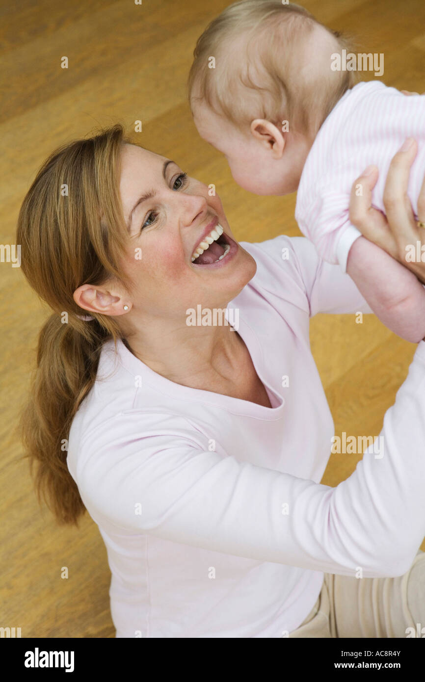 High angle view of a mid adult woman lifting her baby girl in the air ...