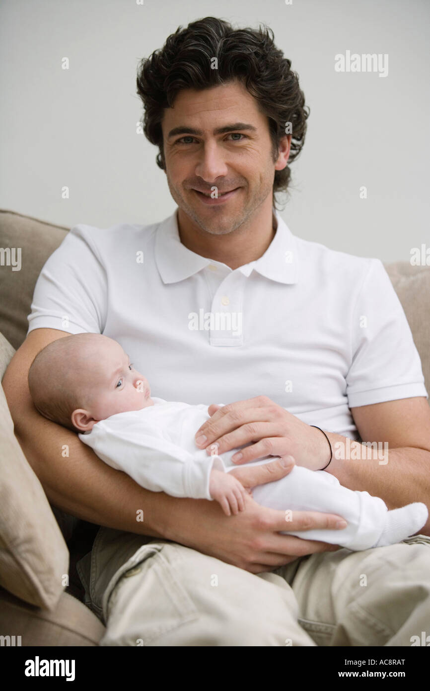 Mid adult man smiling and holding his baby Stock Photo - Alamy