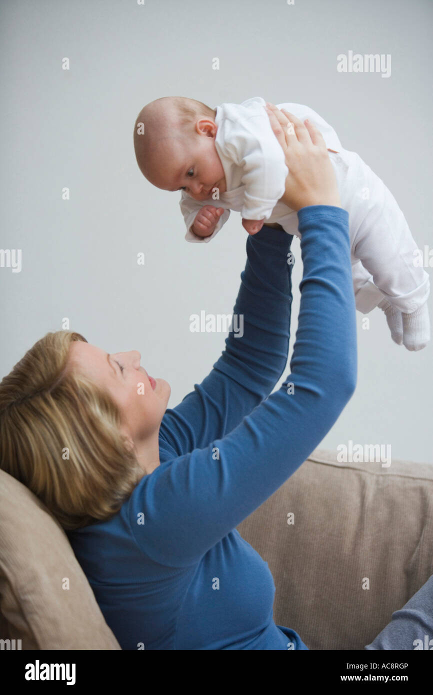 Mid adult woman lifting her baby Stock Photo - Alamy