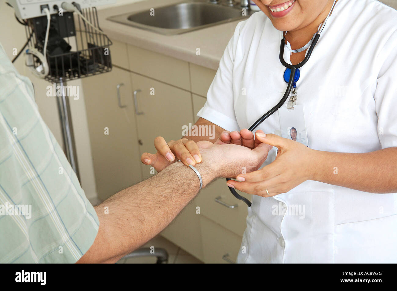 Female nurse checking the pulse of a patient Stock Photo - Alamy