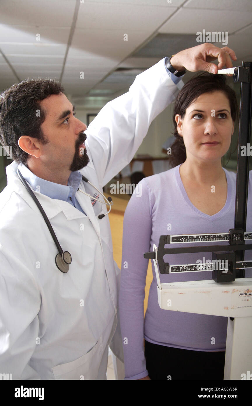 Male doctor measuring the height and weight of a patient Stock Photo ...