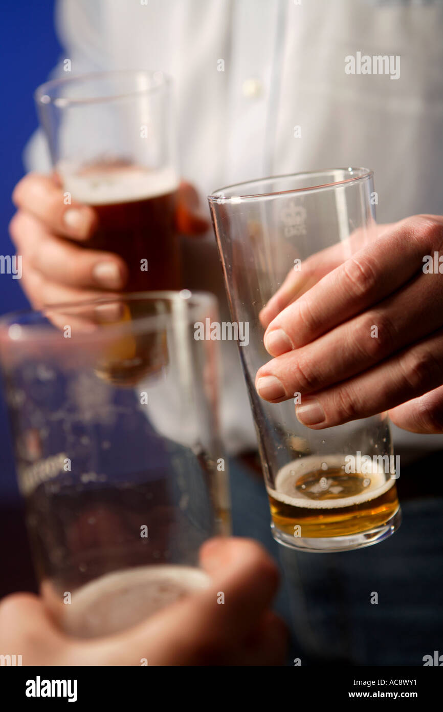 Holding half full pint glasses of beer Stock Photo - Alamy