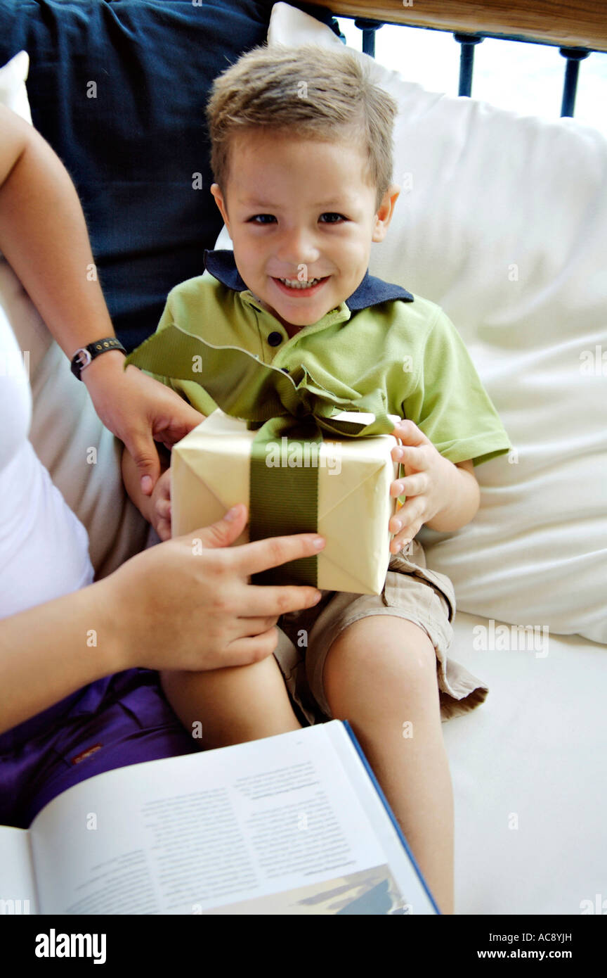 Mid section view of a woman giving a gift to her son sitting on her lap ...
