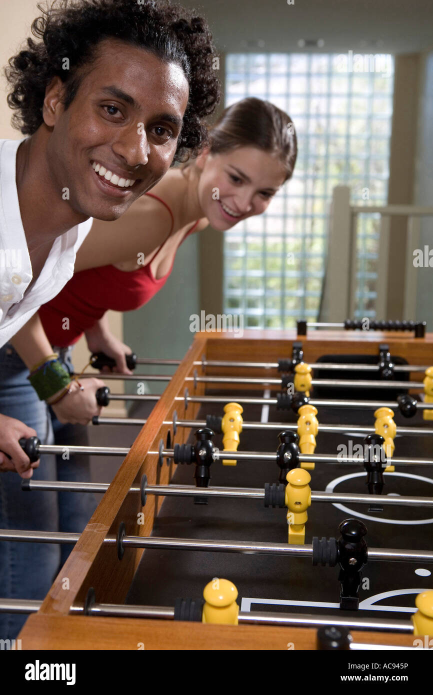 Teenage girl and a young man playing foosball Stock Photo - Alamy