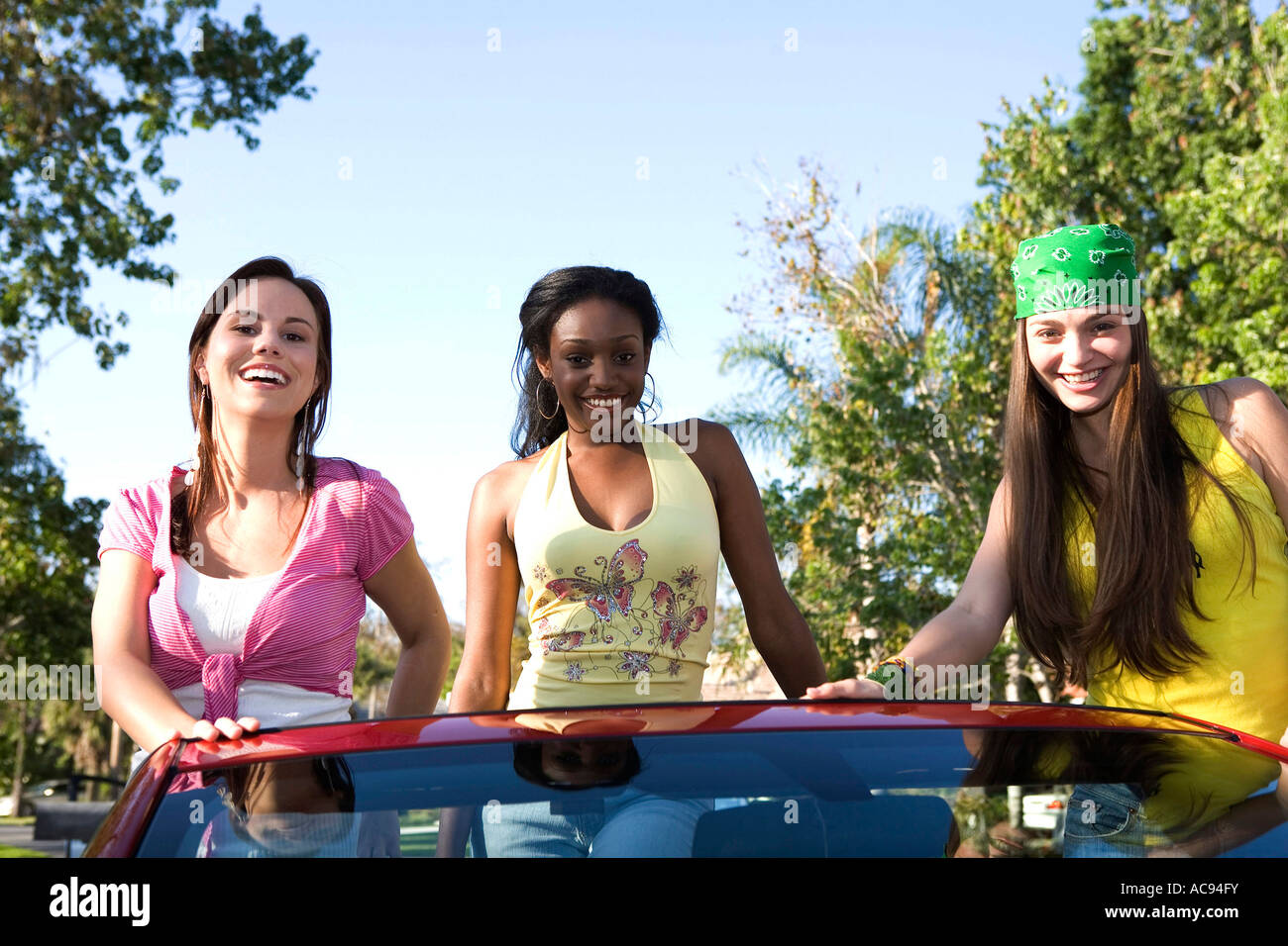 Two teenage girls and a young woman standing in a convertible car Stock ...