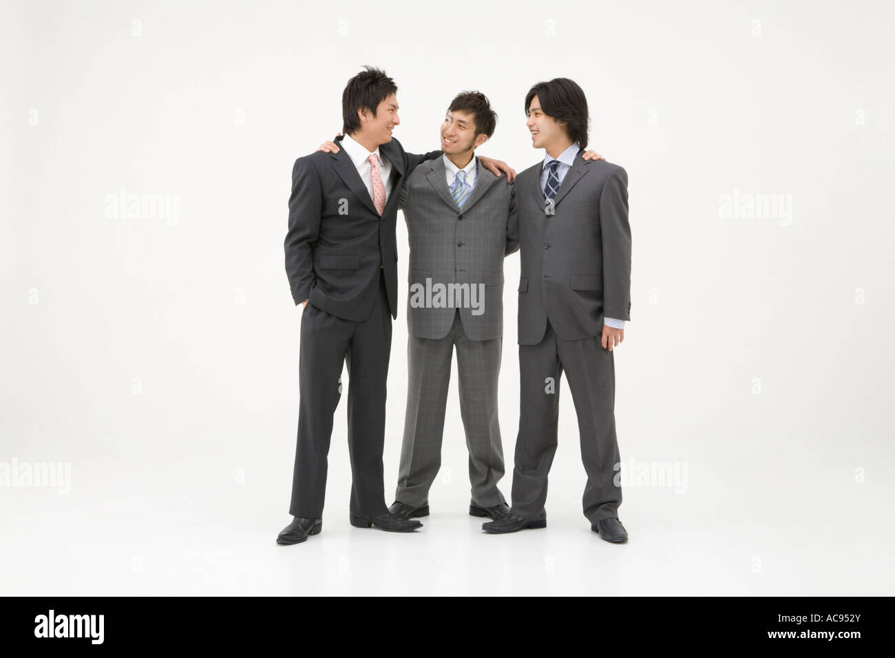 Three businessmen standing with arms around each other Stock Photo - Alamy