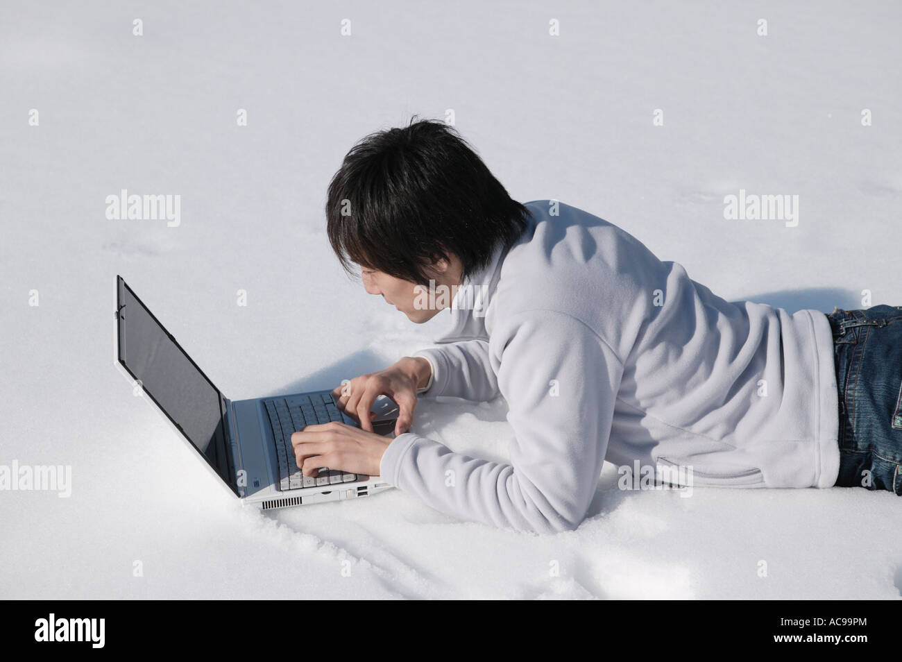 Young man using computer on snow Stock Photo - Alamy