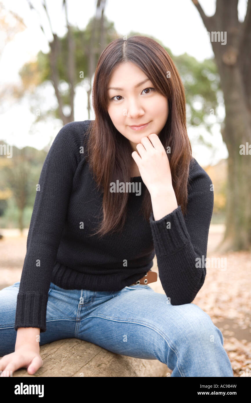 Young woman sitting on log Stock Photo - Alamy