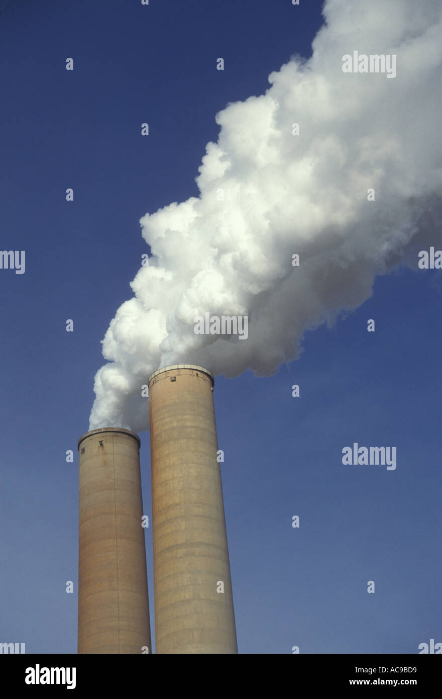 Two smoke stacks with billowing smoke against a blue sky Stock Photo ...