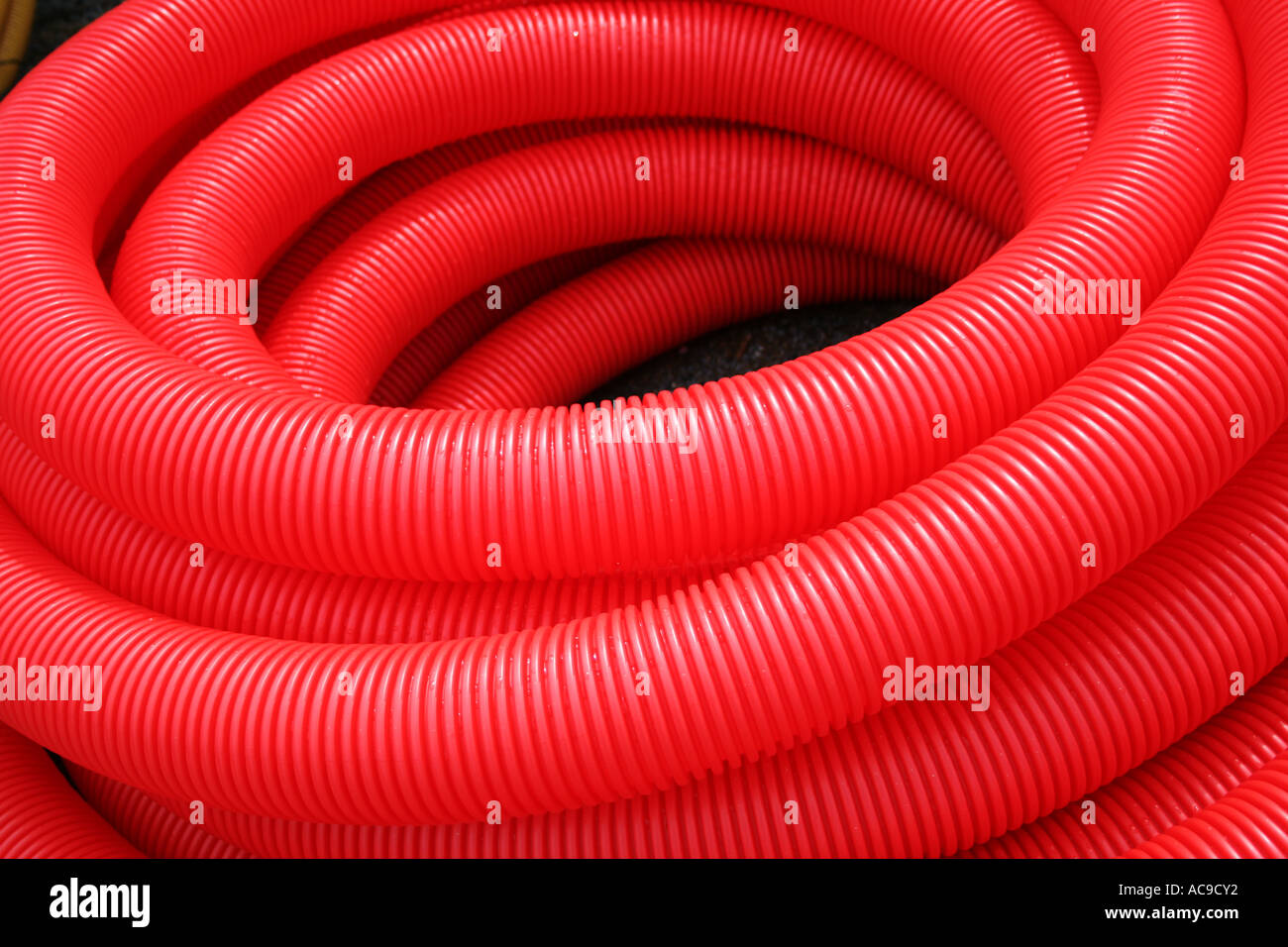 Vibrant red corrugated pipes stacked in a spiral Stock Photo - Alamy