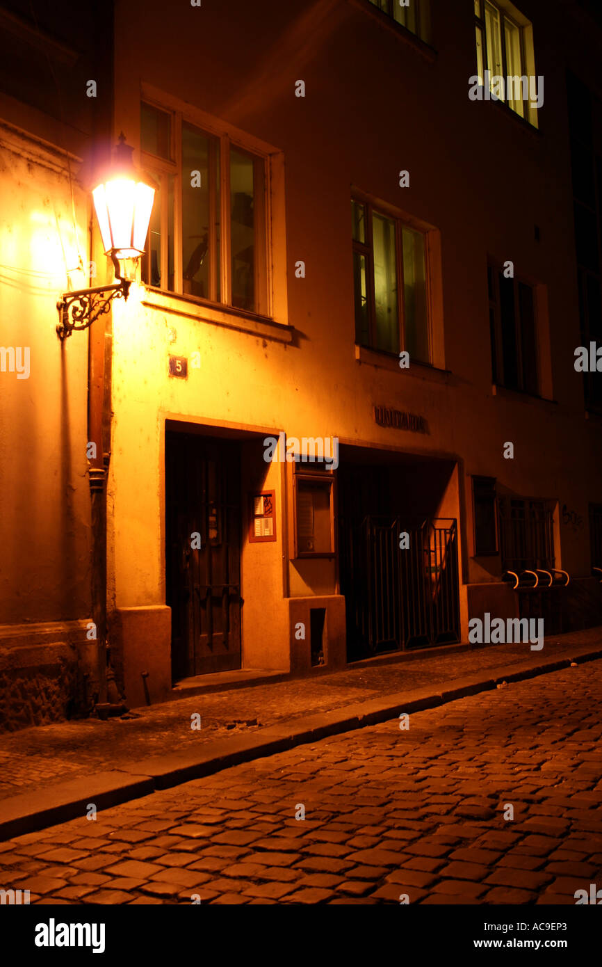 Night street scene in Prague with a lit street lamp casting a warm glow ...