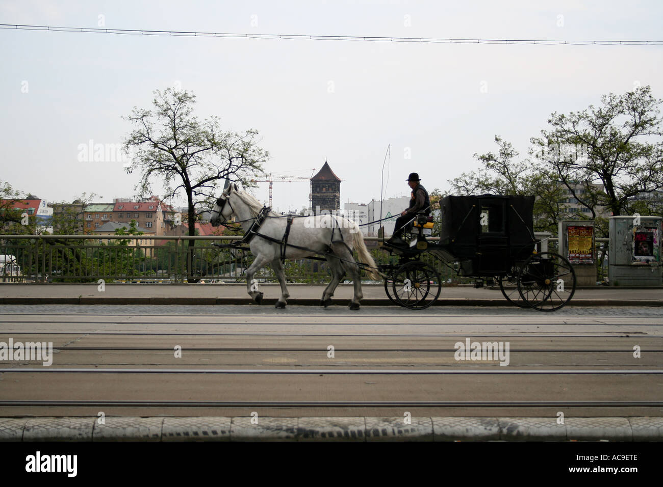 Horse-drawn carriage crossing a bridge in Prague with a driver in a hat, cityscape in the ...