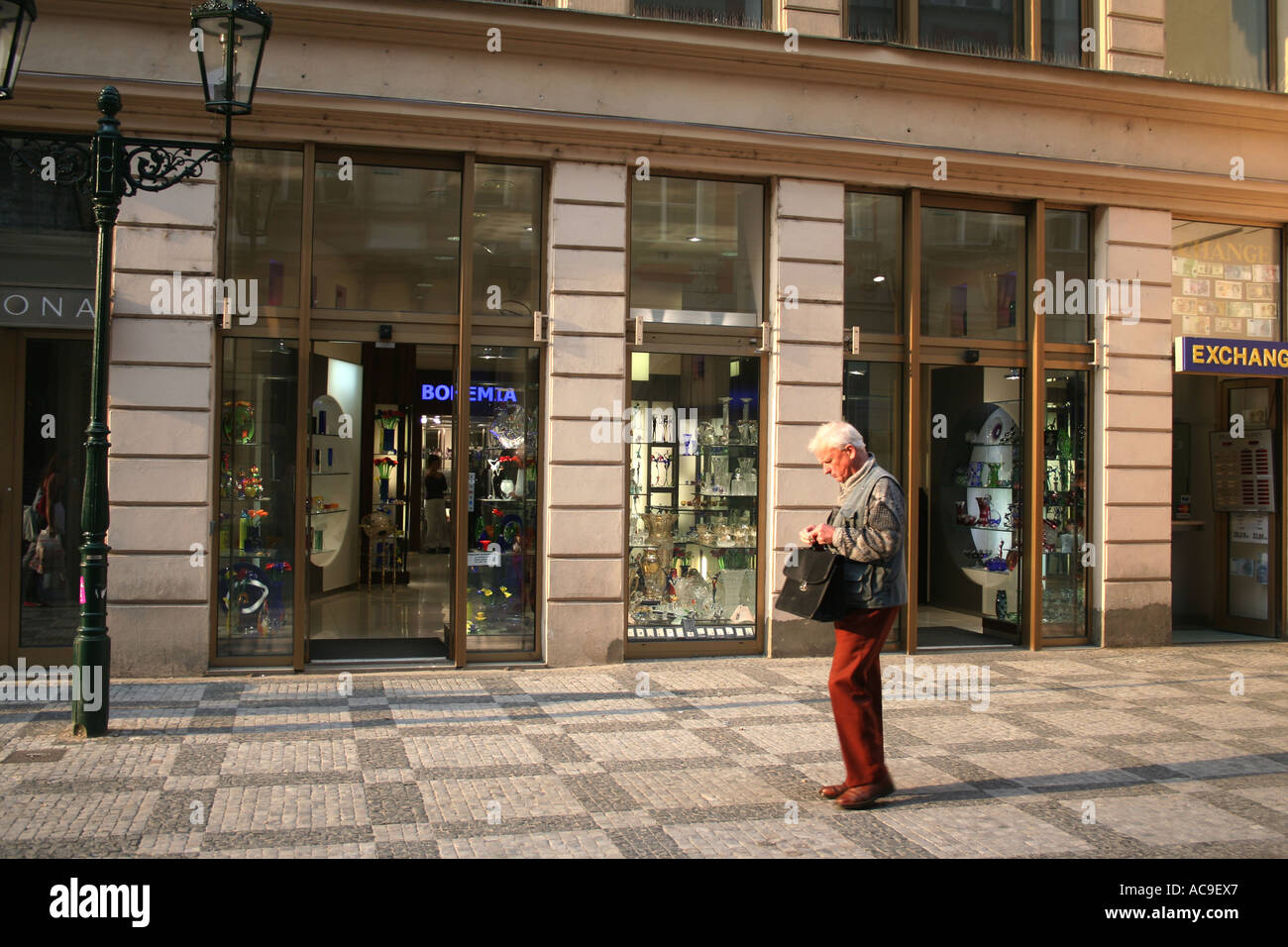 Man walking past a glassware shop in Prague with storefront windows ...