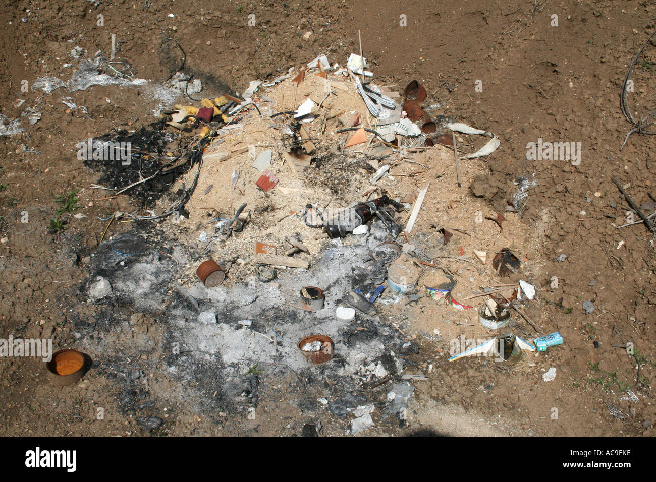 Burned trash and debris on dry ground illustrating environmental ...