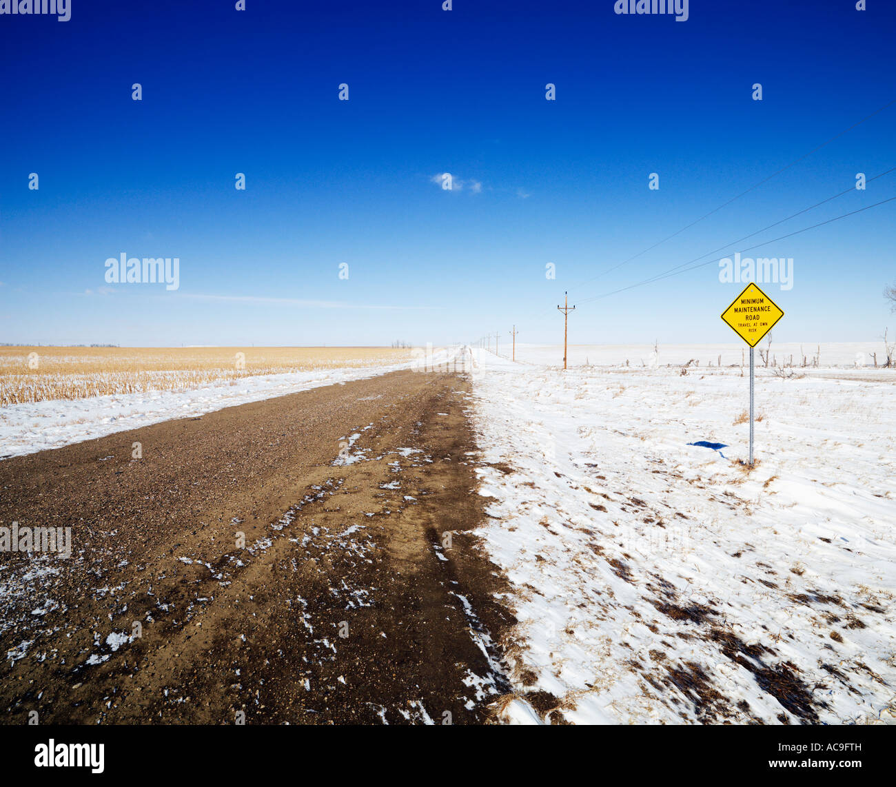 Desolate dirt road with snow covered ground and road sign Stock Photo ...