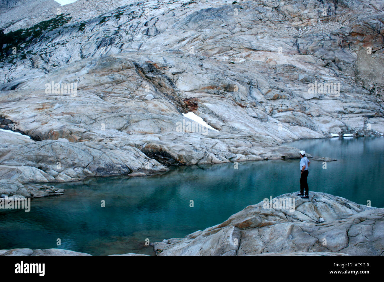 A hiker enjoys the view down to a high alpine lake below Mount Blum ...