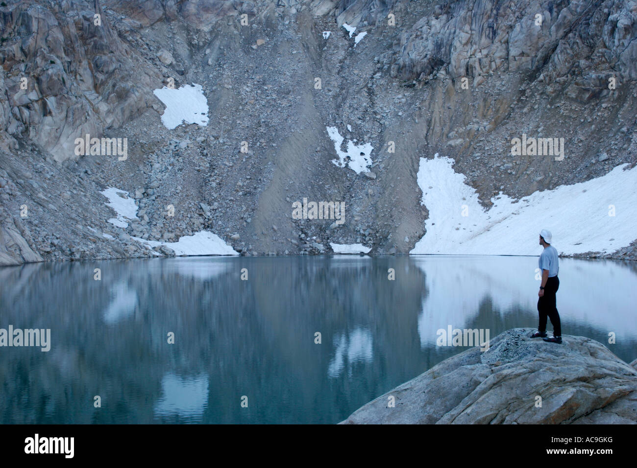 A hiker enjoys the view down to a high alpine lake below Mount Blum ...