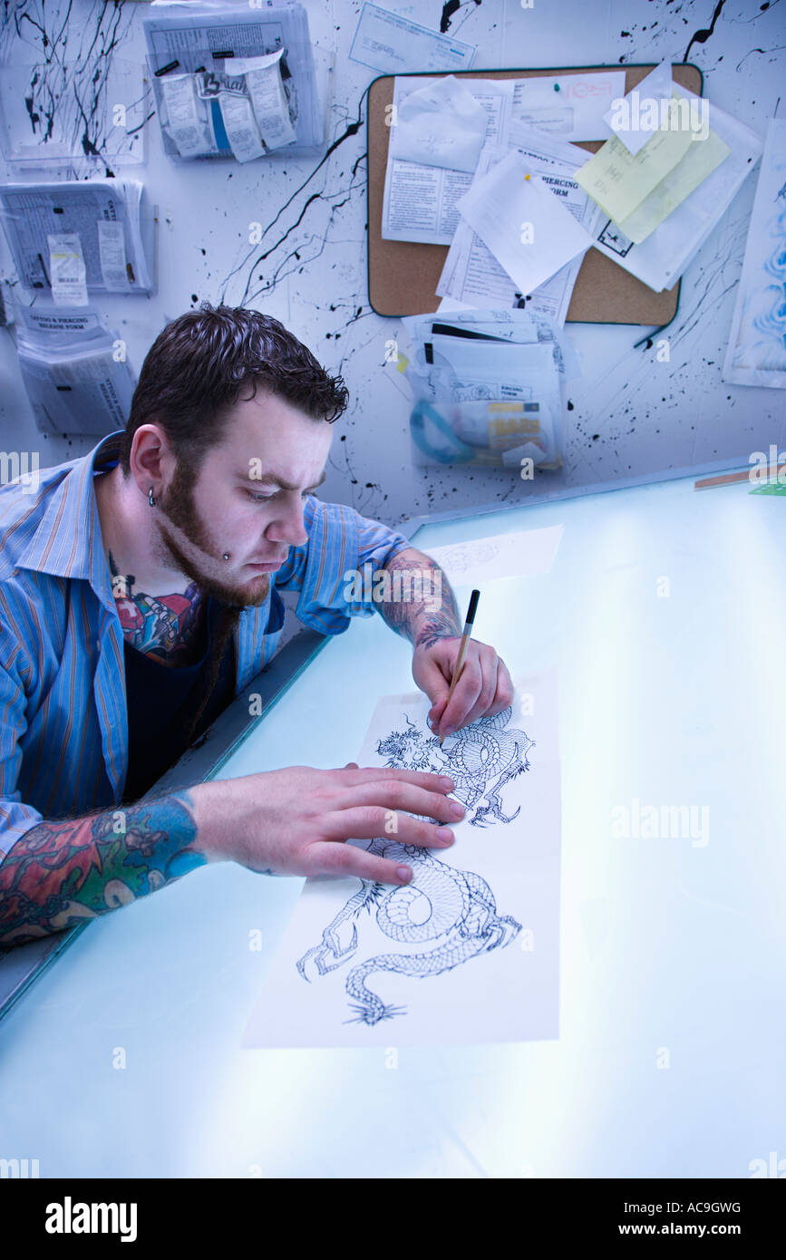 Caucasian male tattoo artist drawing tattoo on light table Stock Photo ...