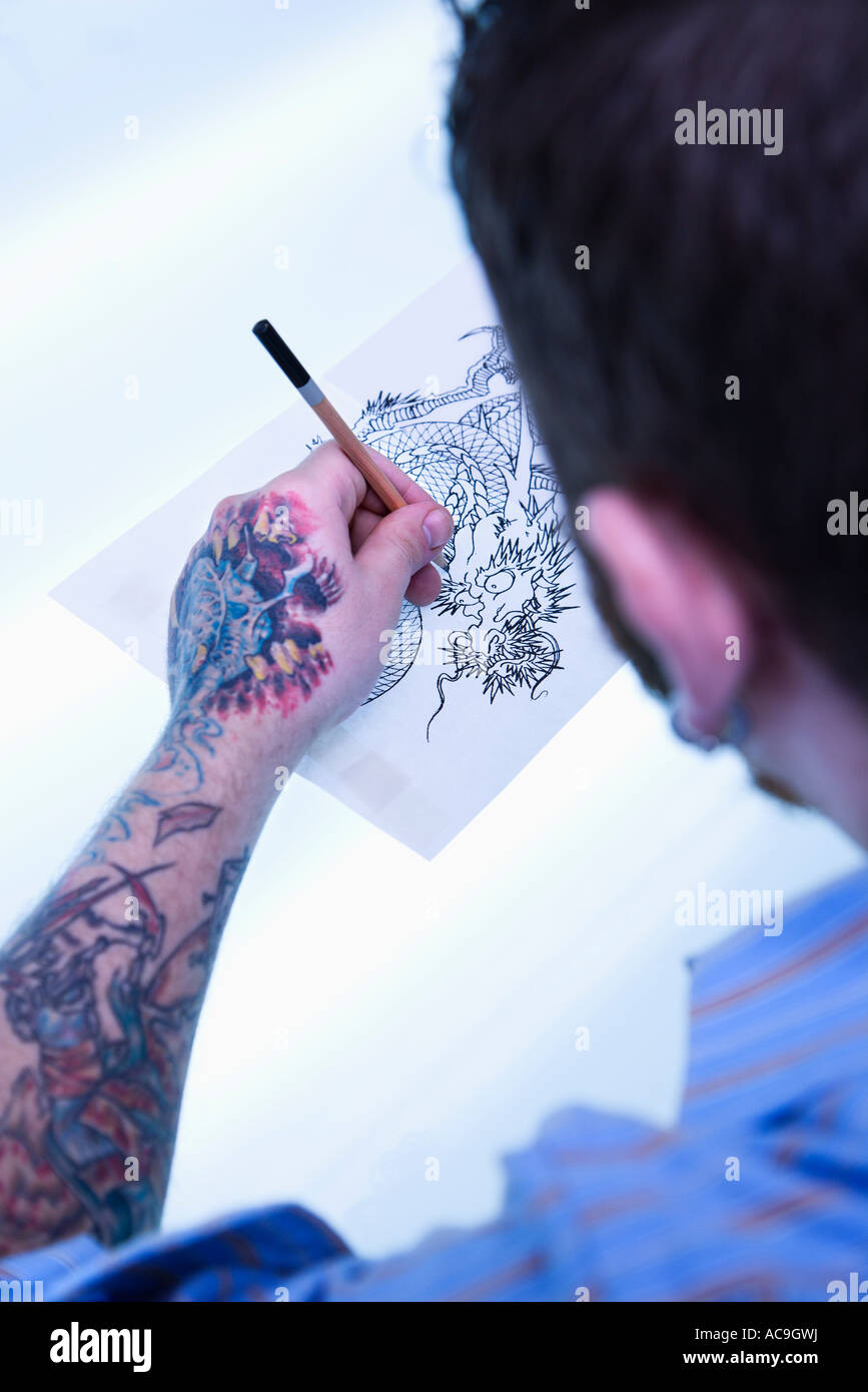 Caucasian male tattoo artist drawing tattoo on light table Stock Photo ...