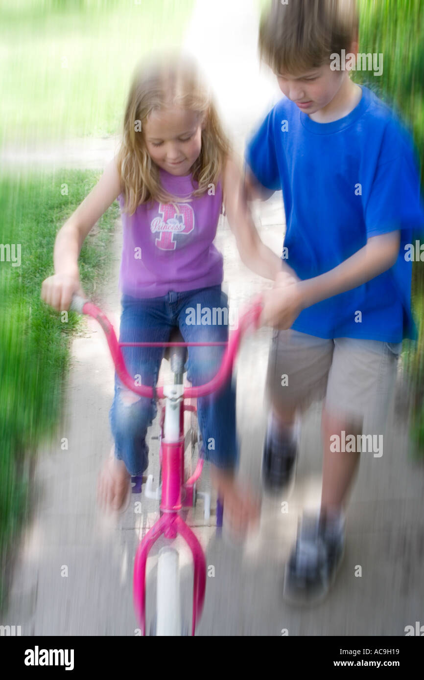 Child helping friend ride bike hi-res stock photography and images - Alamy