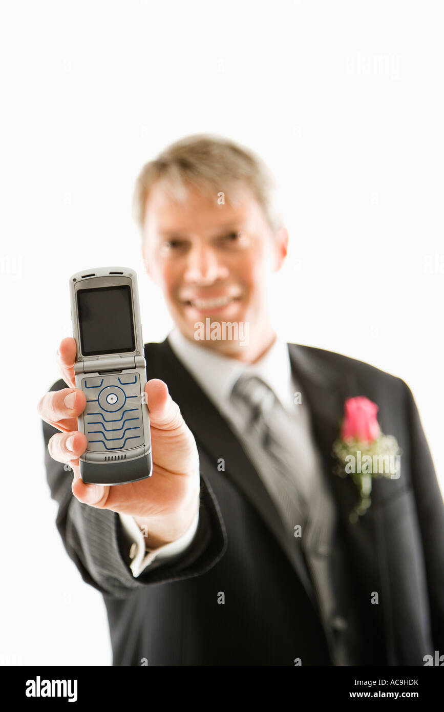 Caucasian groom holding out his cellphone towards viewer Stock Photo ...