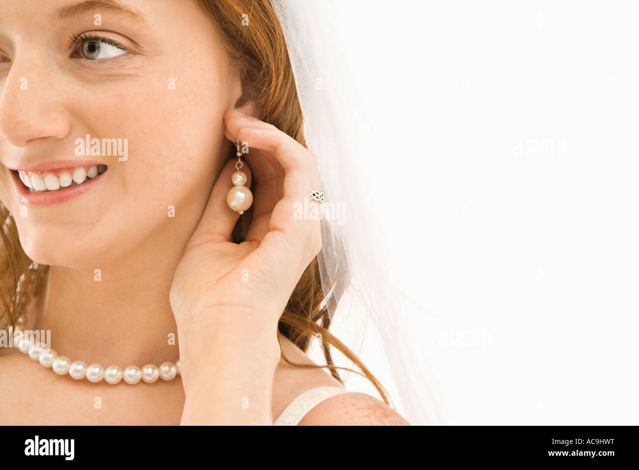 Caucasian bride adjusting her earring Stock Photo - Alamy