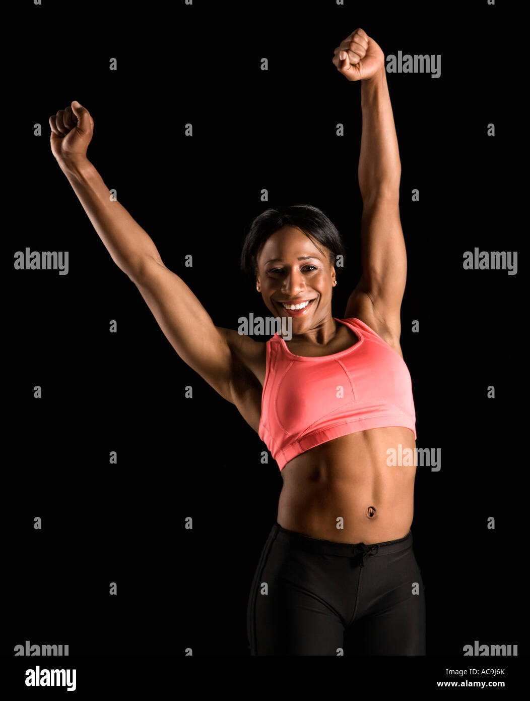 Smiling African American young adult woman in sports bra stretching ...