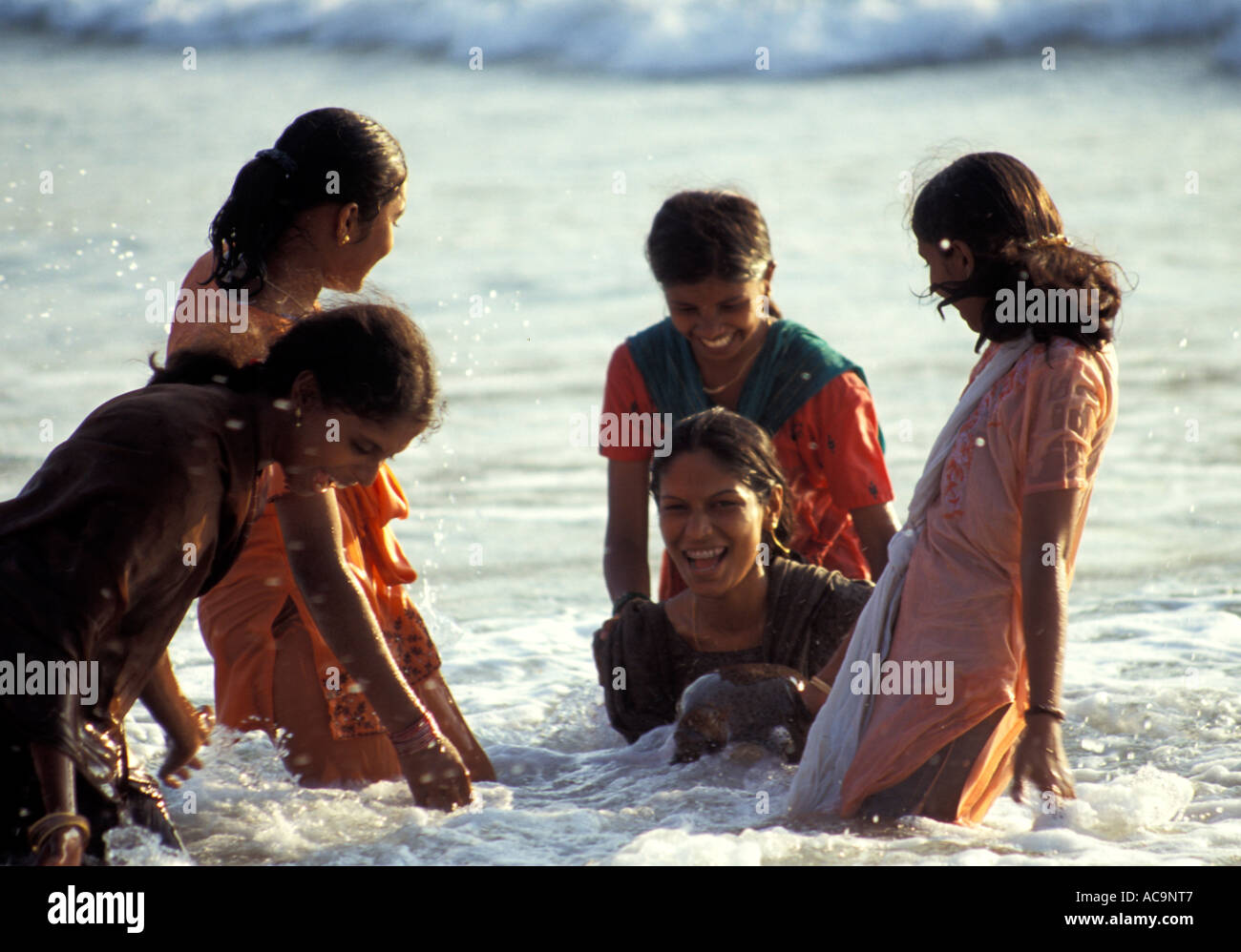 Young Indian women bathe in sea wearing saris, Gokarna, Karnataka ...
