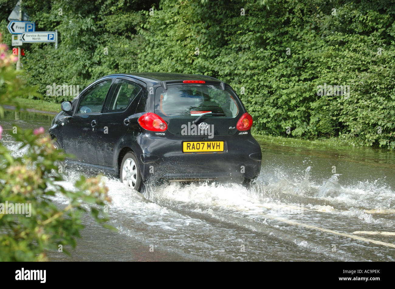 A motor car on a road driving through flood water Stock Photo - Alamy
