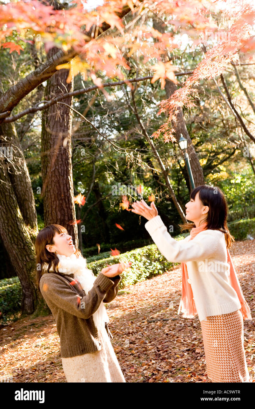 Two young women catching falling leaves Stock Photo - Alamy