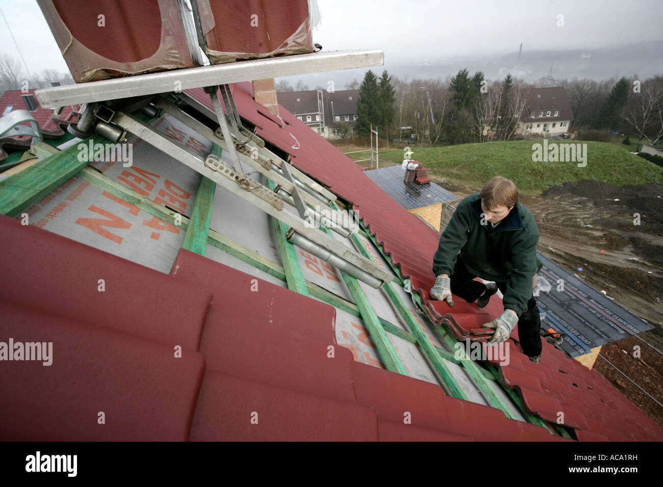 Roof tilers tiling a pointed roof of an apartment house, Essen, North ...