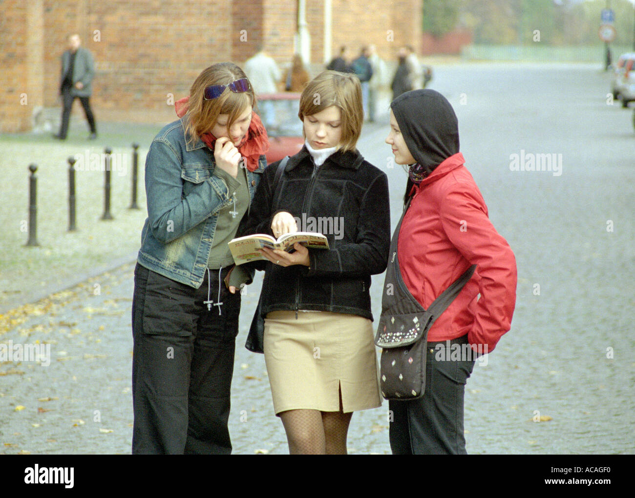 Three girls read a guidebook in Poland Stock Photo - Alamy