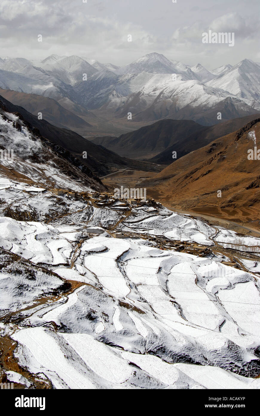 Village on snow covered slope with terraces and mountains Yerpa Tibet ...
