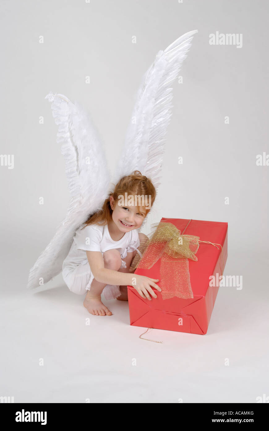 Little christmas angel with a christmas present Stock Photo - Alamy
