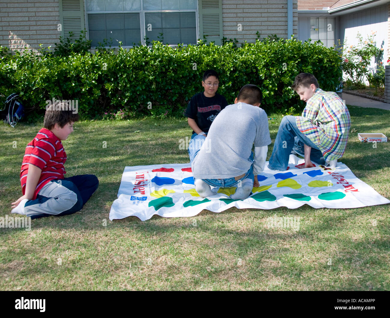 Ethnically diverse boys playing twister game on lawn during the summer ...