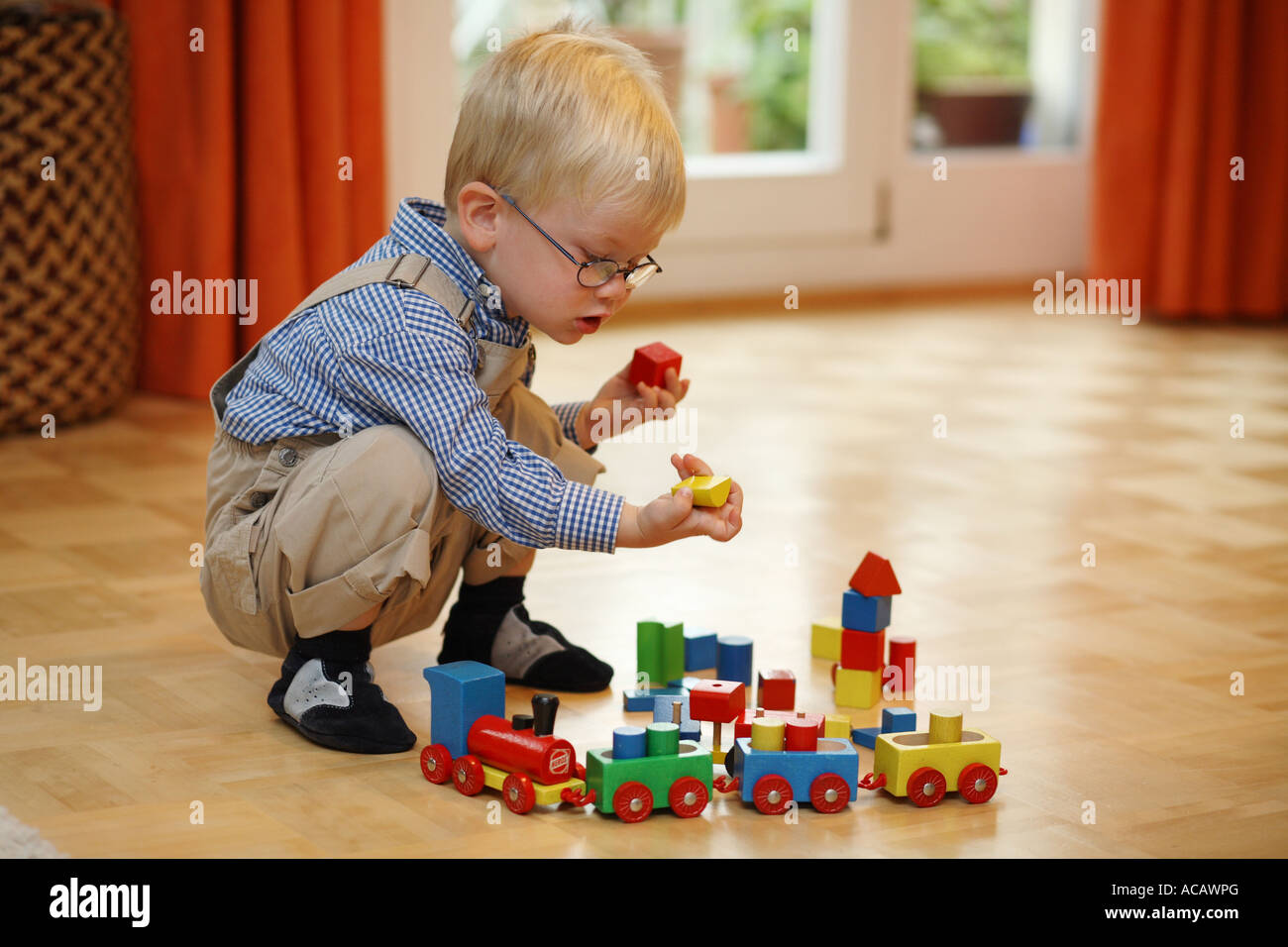 Little boy plays with a wooden toy-train Stock Photo - Alamy