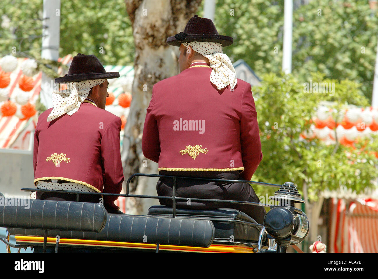 Two coachmen in traditional red uniforms driving through the April Fair ...