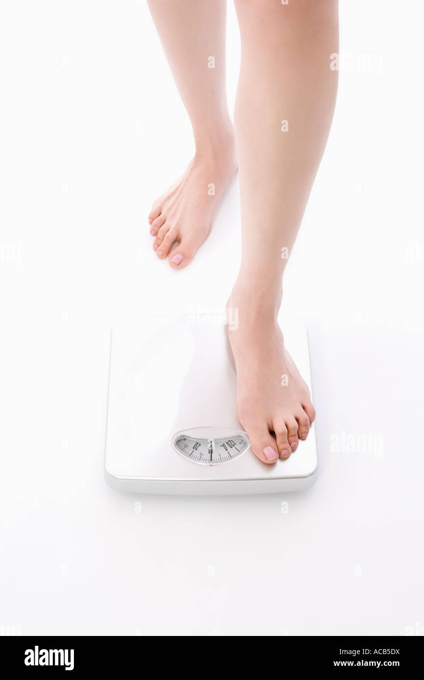 Woman stepping on bathroom scale Stock Photo - Alamy