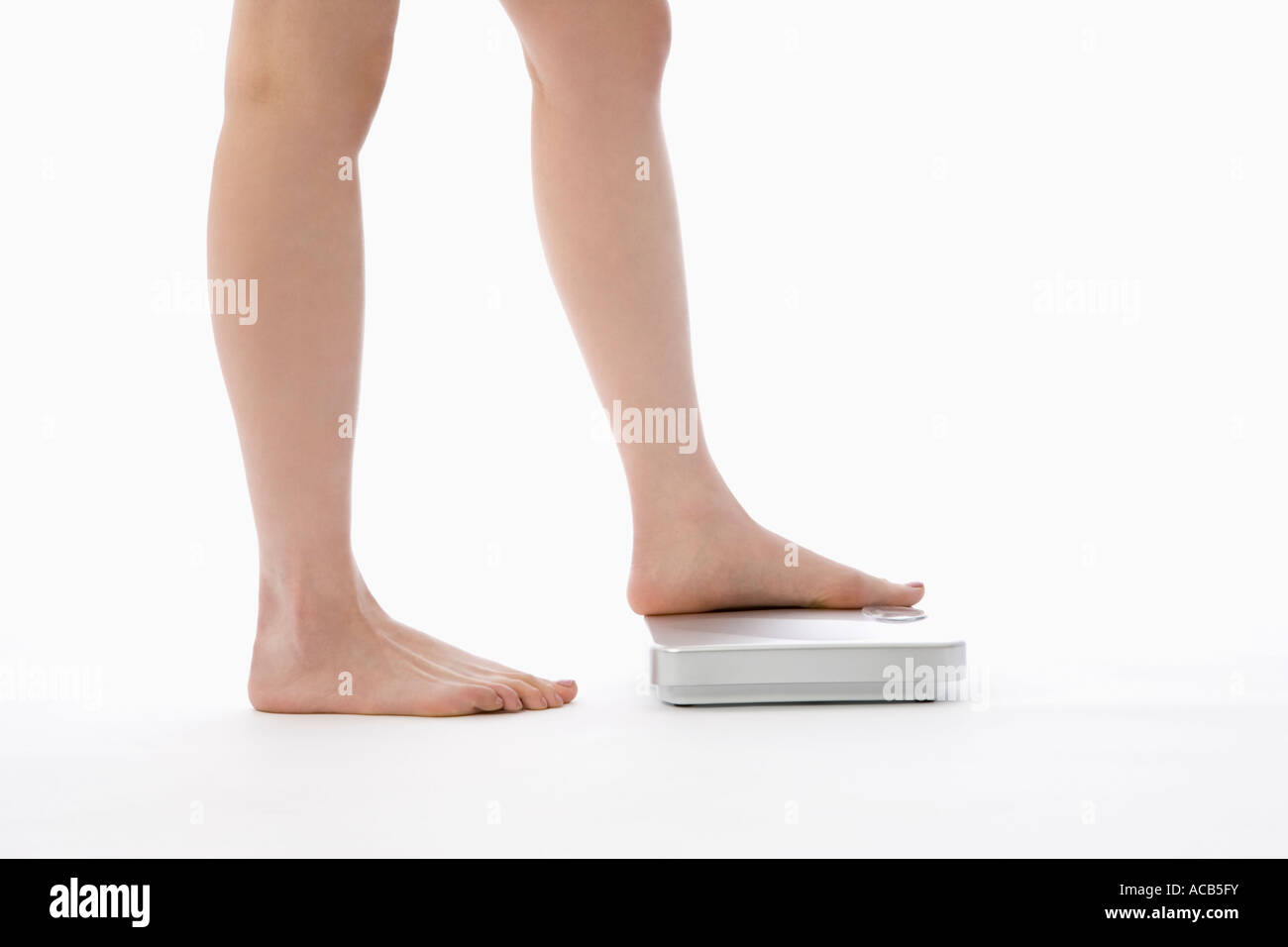 Woman stepping on bathroom scale Stock Photo - Alamy