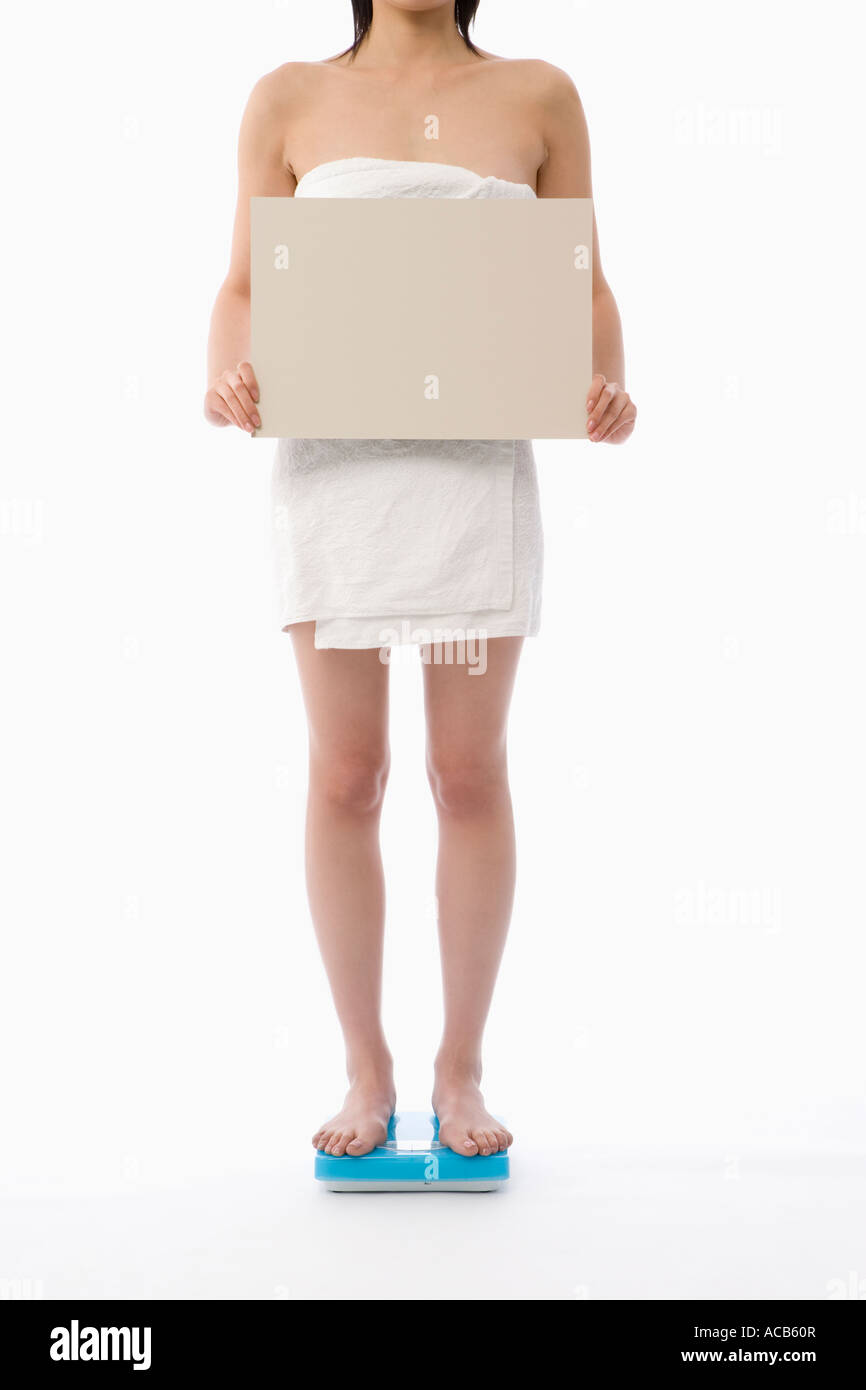 Woman standing on bathroom scale holding blank placard Stock Photo - Alamy