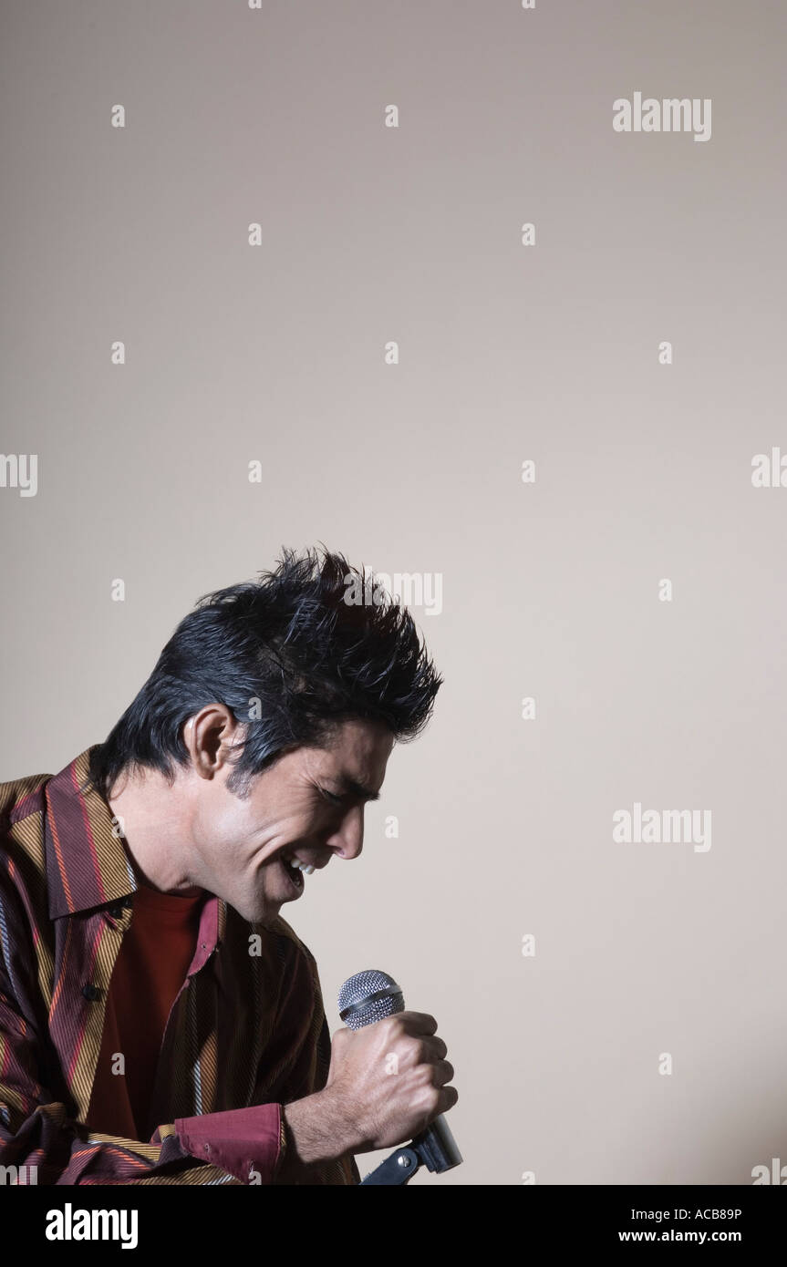 Side profile of a young man singing into a microphone Stock Photo - Alamy