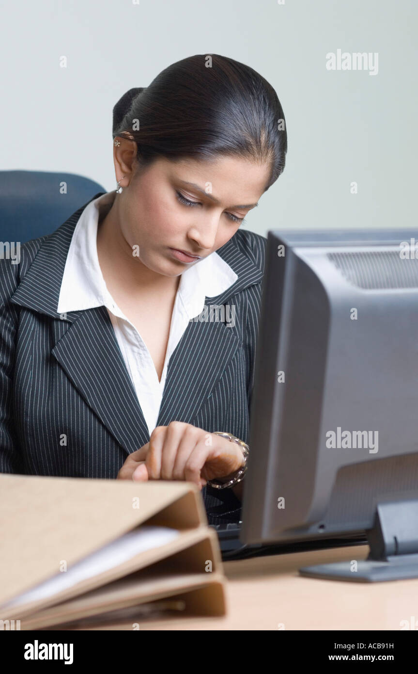 Businesswoman checking the time in front of a computer Stock Photo - Alamy