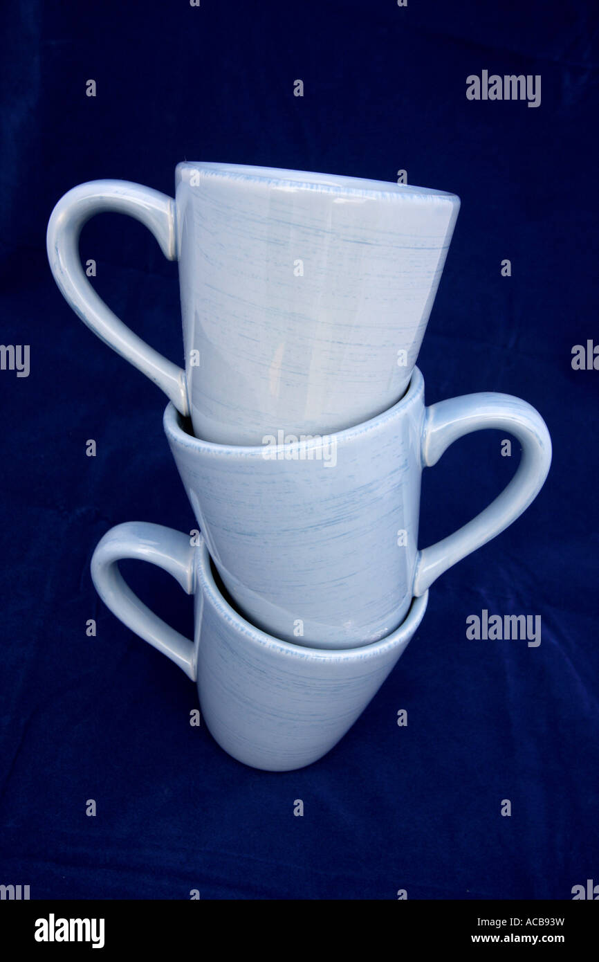 FRONT VIEW THREE LIGHT BLUE COFFEE CUPS STACKED AGAINST BLUE BACKGROUND ...