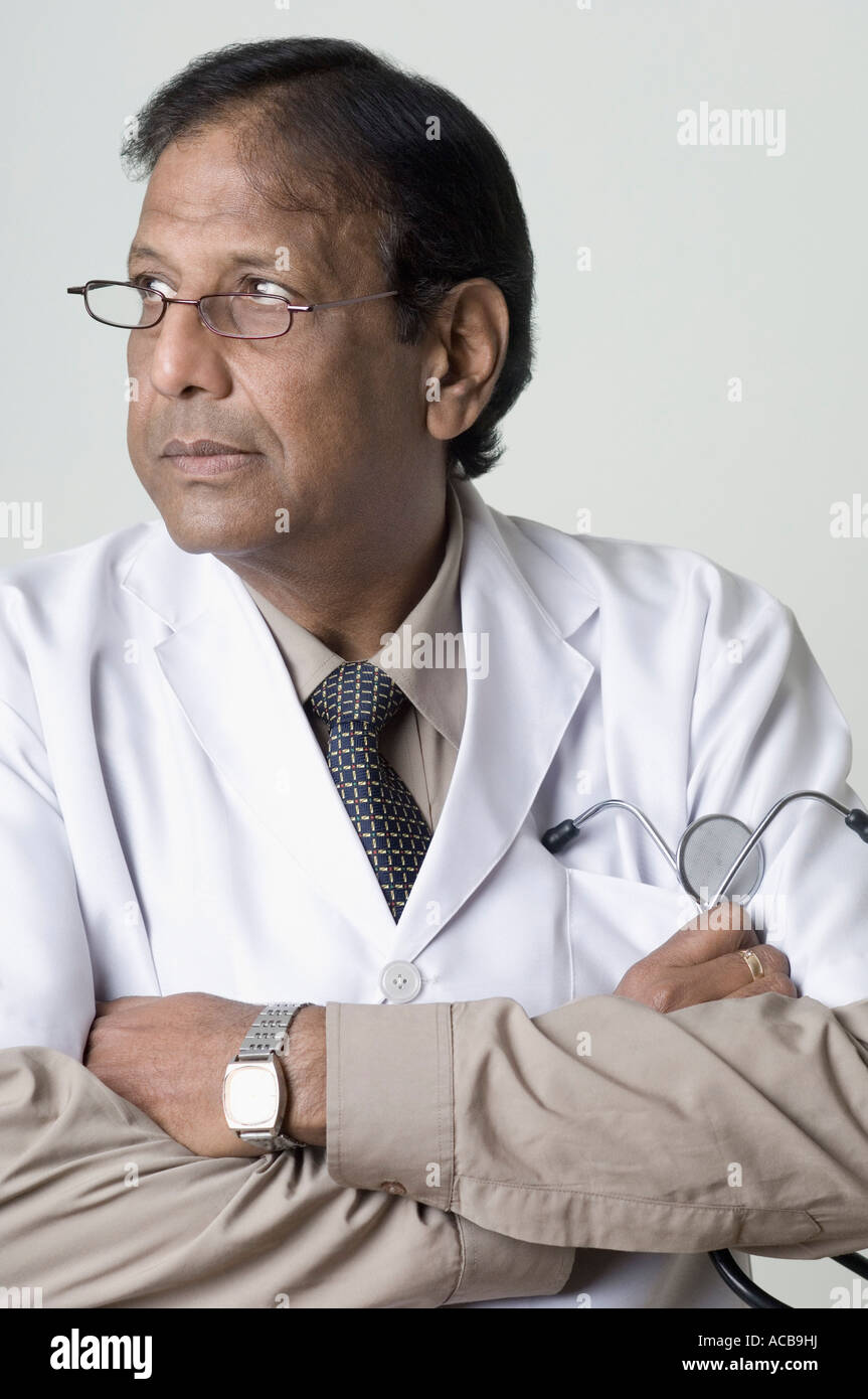 Close-up of a male doctor looking sideways with his arms crossed Stock ...