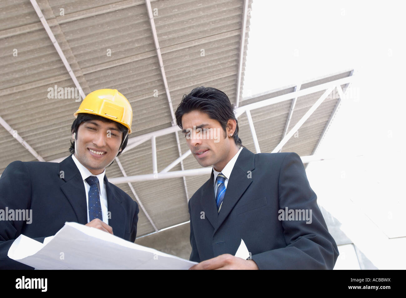 Two architects discussing a blueprint at a construction site Stock ...