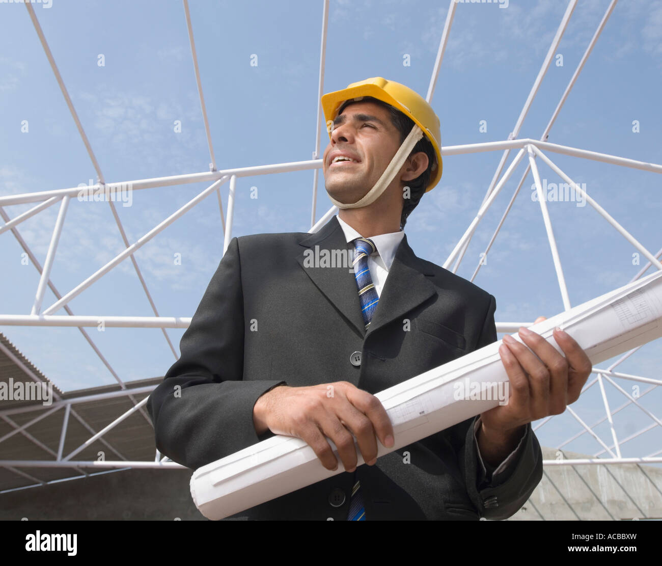 Low angle view of a male architect holding a blueprint at a ...